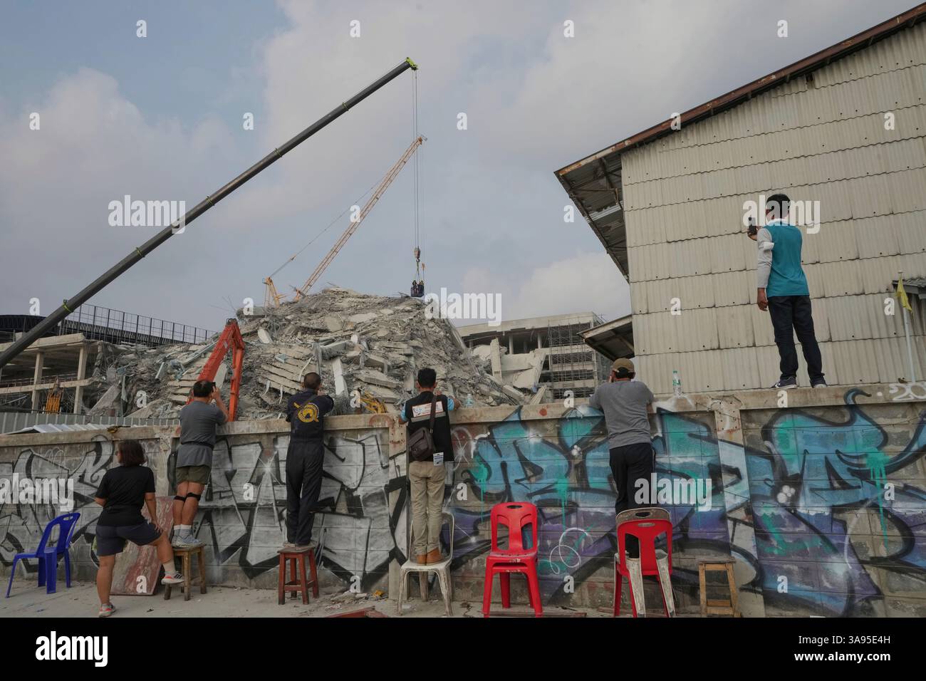 people watch rescue work underway at the site of an under-construction ...