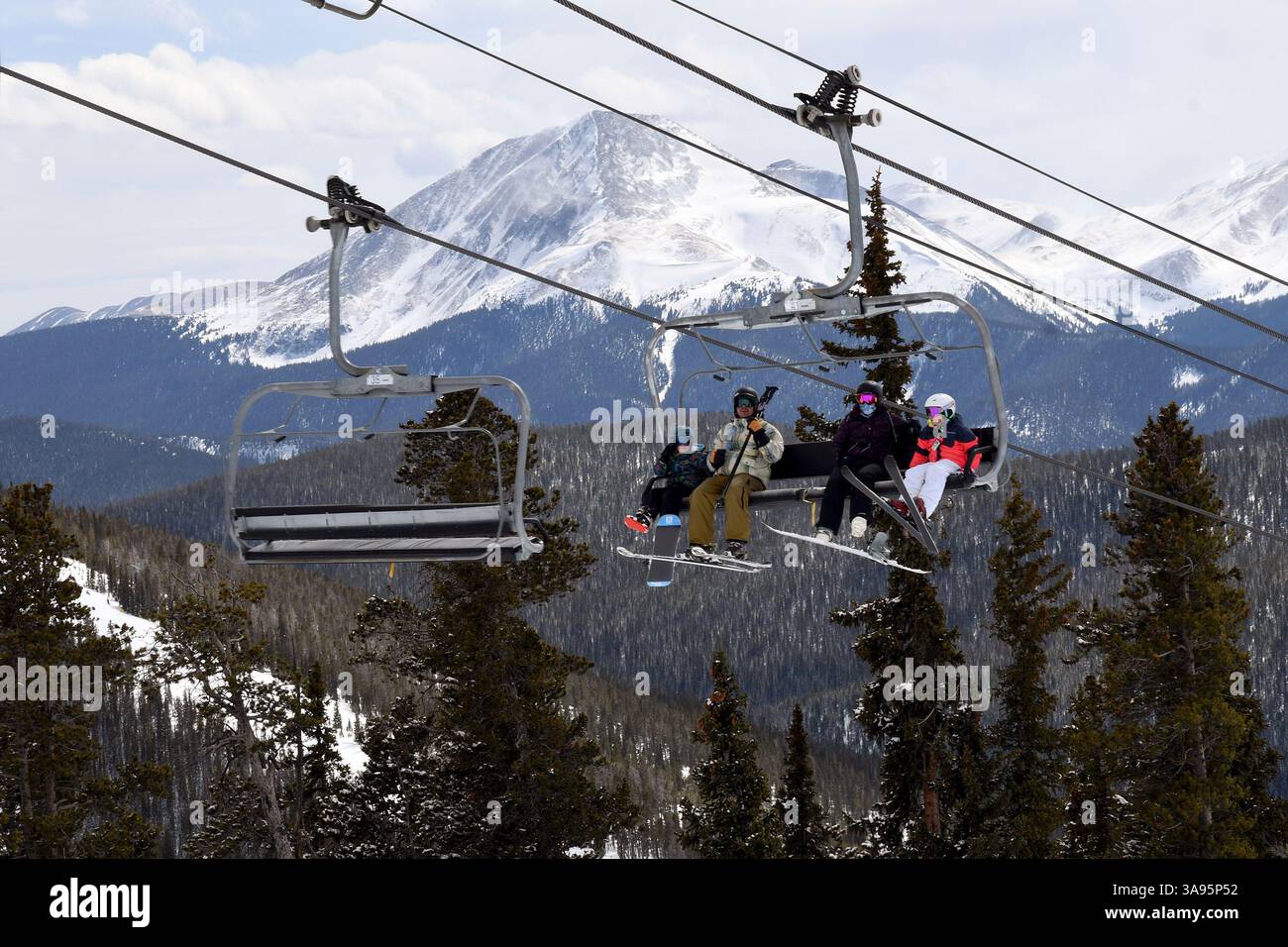 Skiers and snowboarders ride a lift at Keystone Ski Resort in Keystone ...