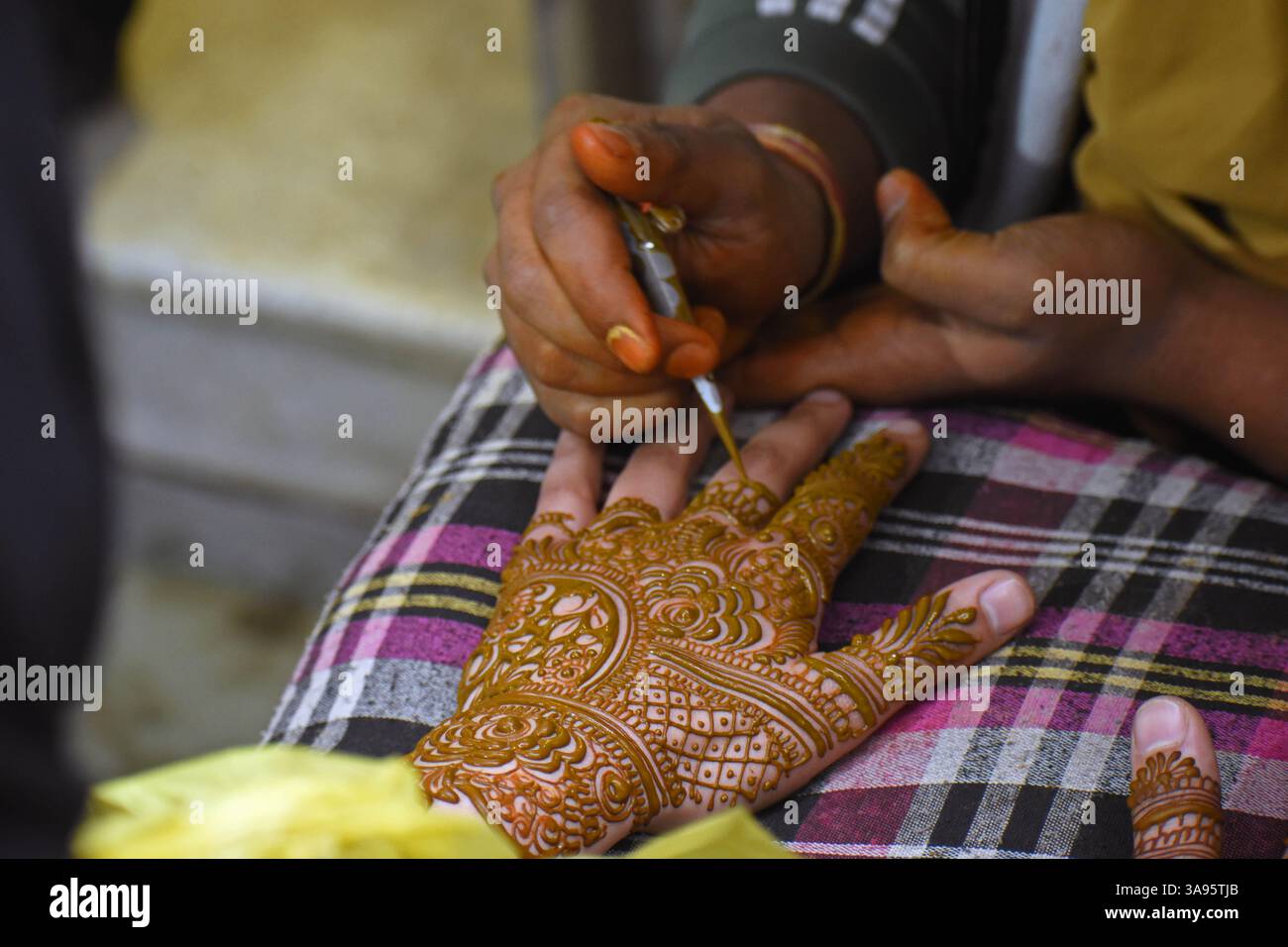 A mehndi artist designs a beautiful mehndi pattern on a Kashmiri girl's ...