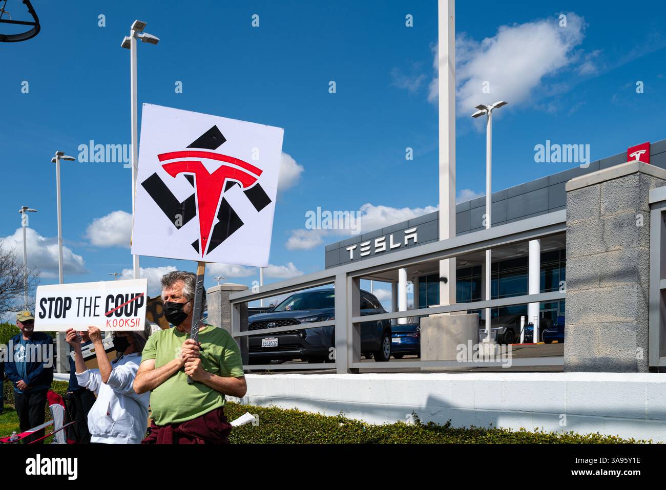 An activist holds a Tesla Swastika sign at an anti-Elon Musk and DOGE ...
