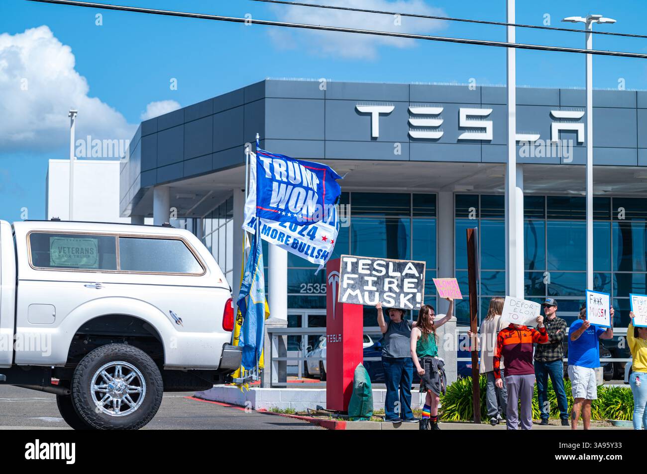 A truck with a Trump Won flag drives past a protester with a Fire Musk ...
