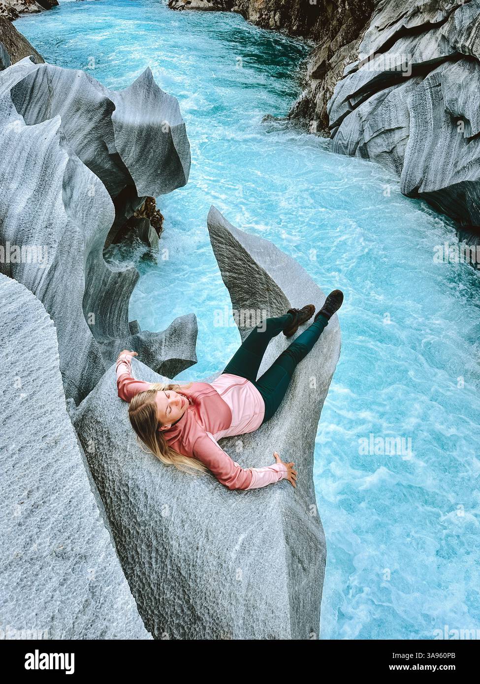Woman tourist traveling solo in Norway laying down on rocky cliff above ...