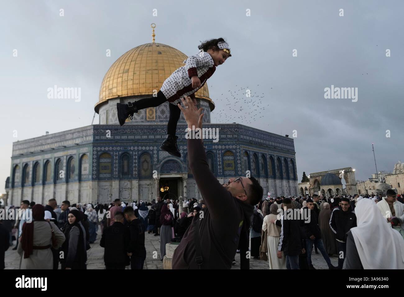 A Palestinian girl is tossed into the air as people gather for Eid al ...