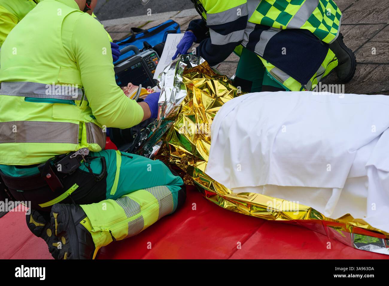 Paramedics providing emergency care to a patient covered with a thermal ...
