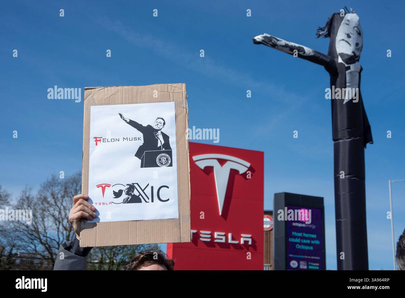 A protester holds his sign front of the inflatable Elon Musk and the ...