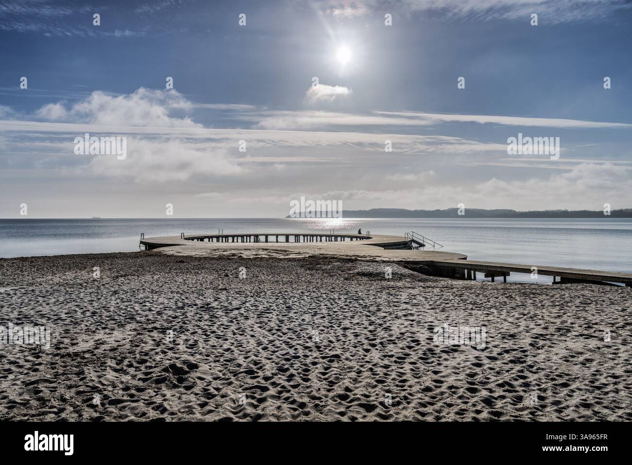 A peaceful beach view showcasing a circular pier extending over calm ...