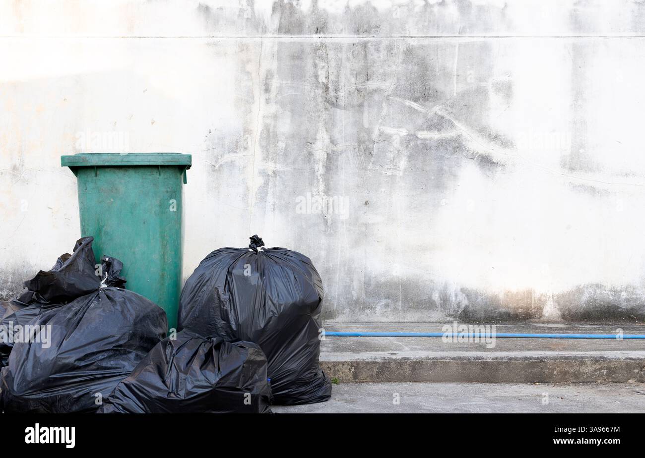 Piles of trash and overflowing bins against a dirty wall with recycling ...