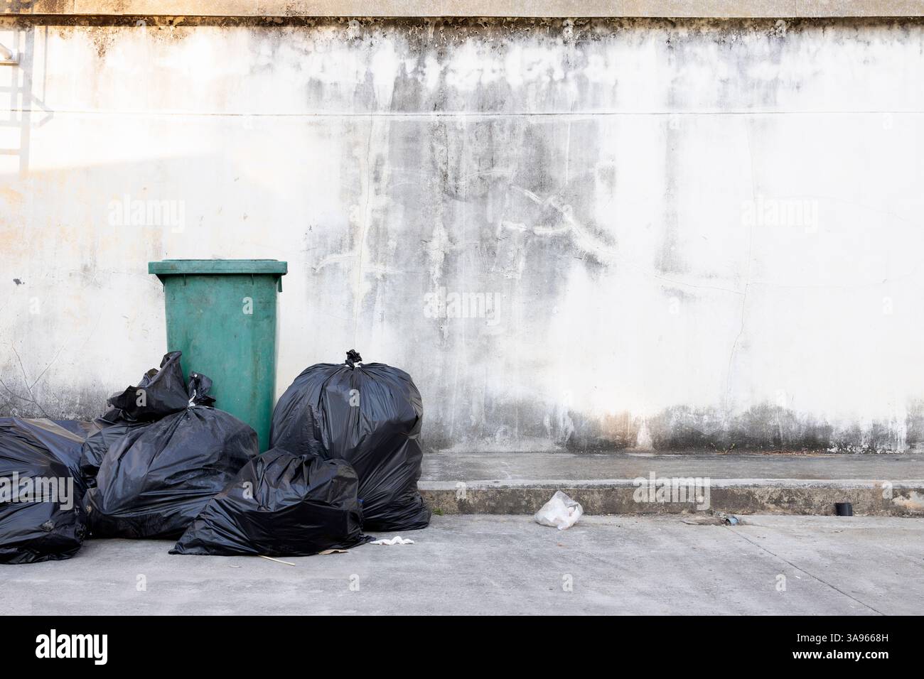 Piles of trash and overflowing bins against a dirty wall with recycling ...