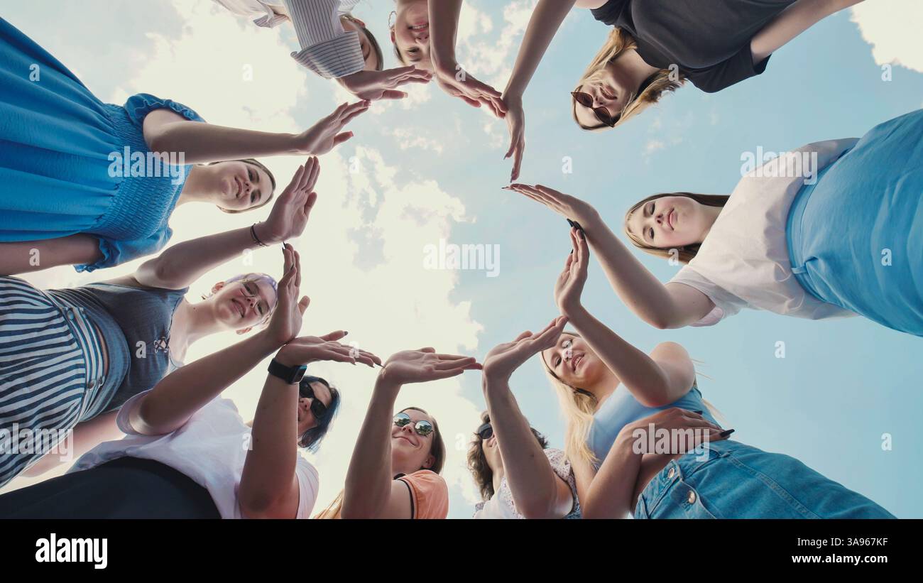 Group of school friends making star shape with their hands against blue ...