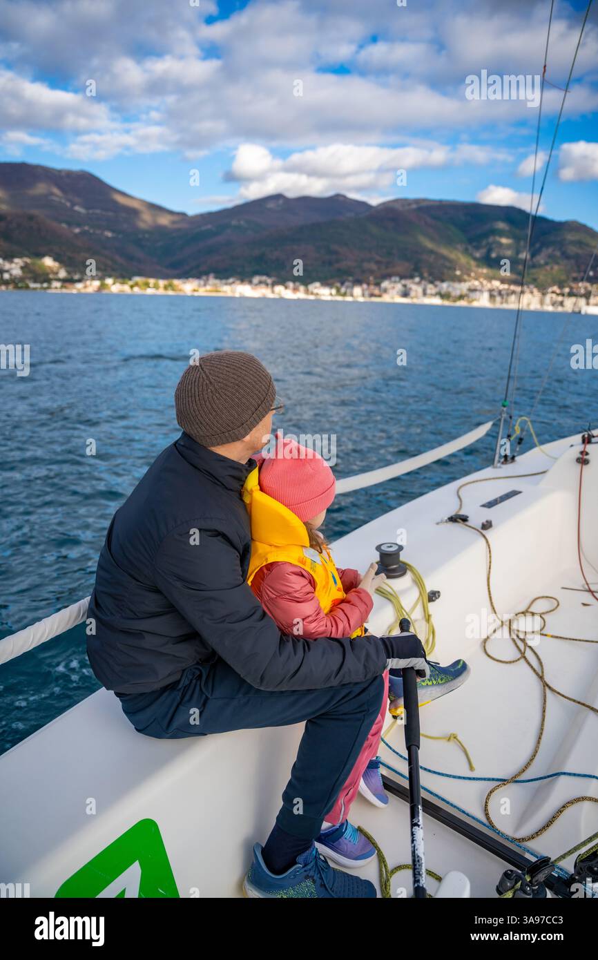 Father instructing daughter on sailing a yacht during training in the ...