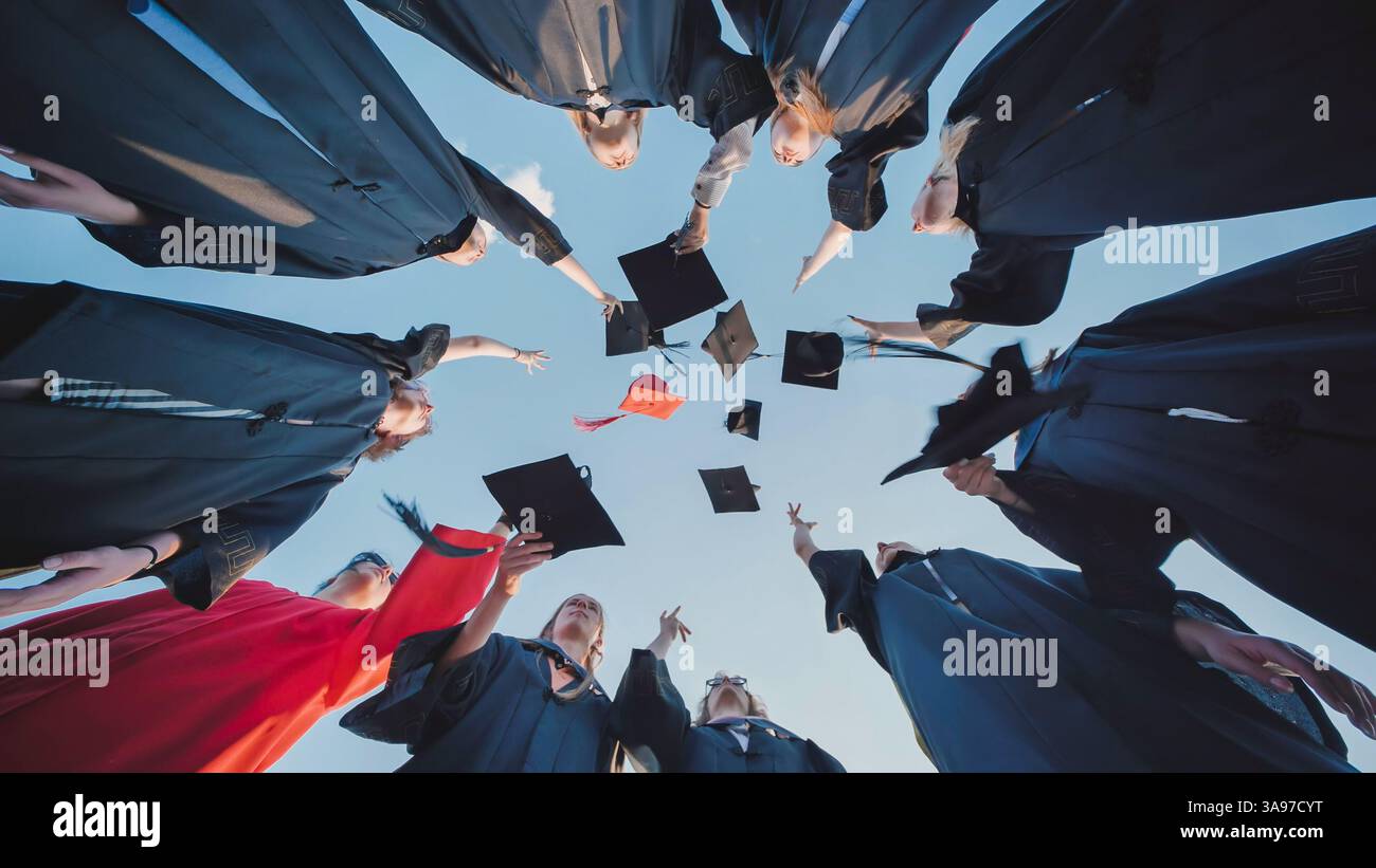 Cheerful graduates celebrate academic success by tossing graduation ...