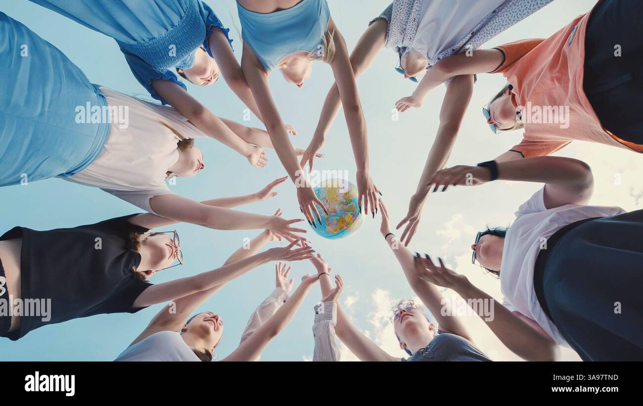 Group of students reaching for a globe, symbolizing their commitment to ...