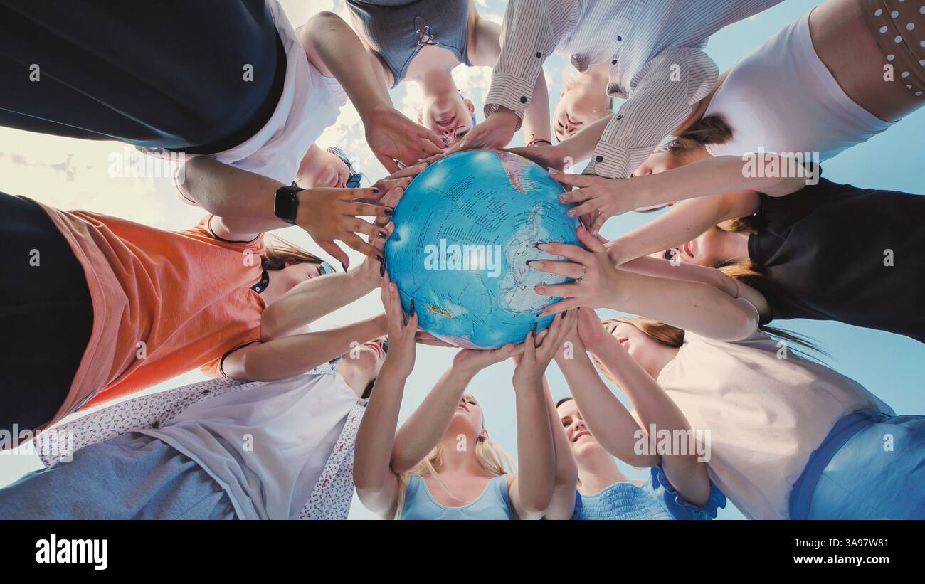 Group of school friends holding a globe, symbolizing environmental ...