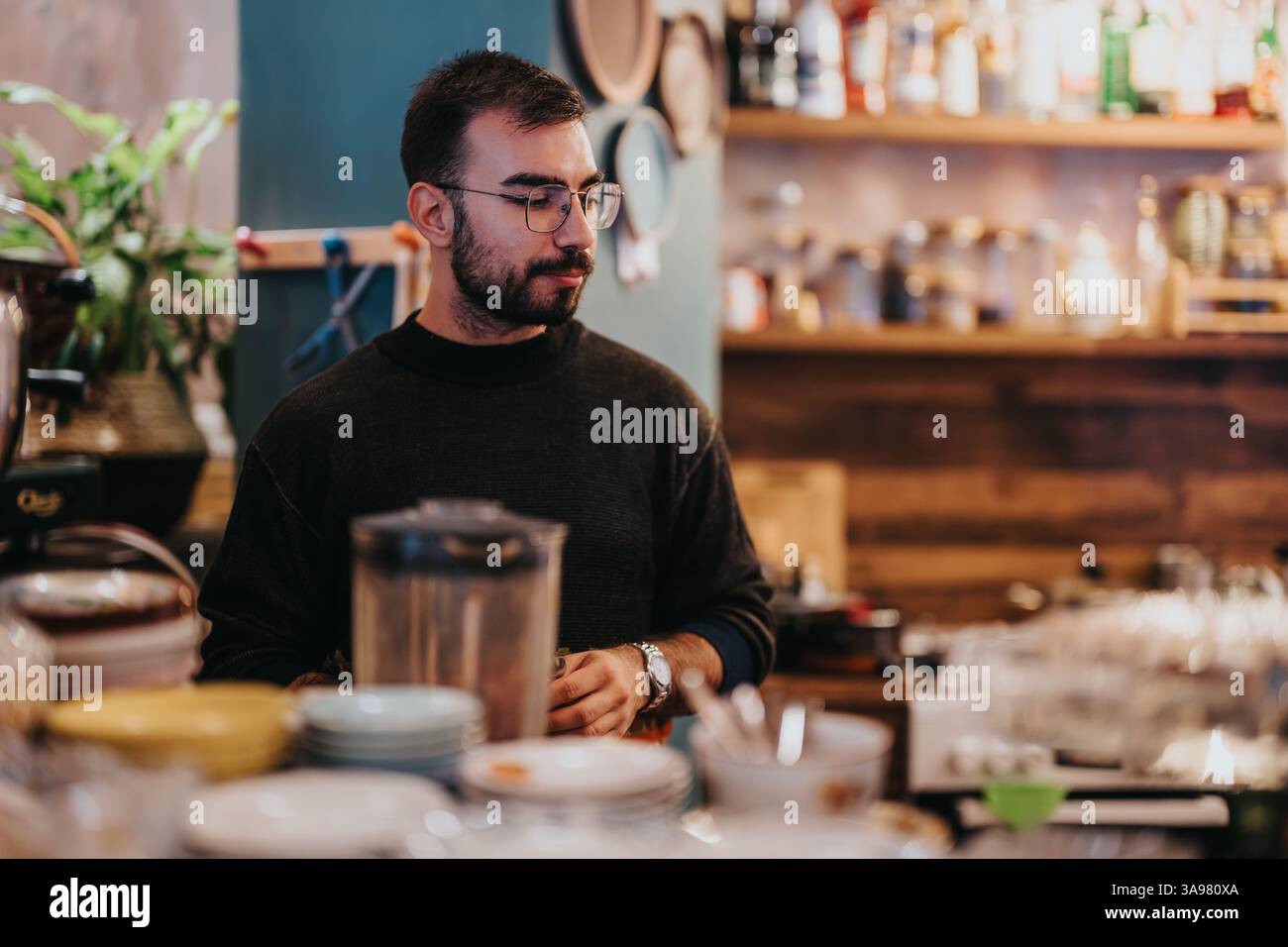 Barista working in a cozy cafe with dishes and warm ambiance Stock ...
