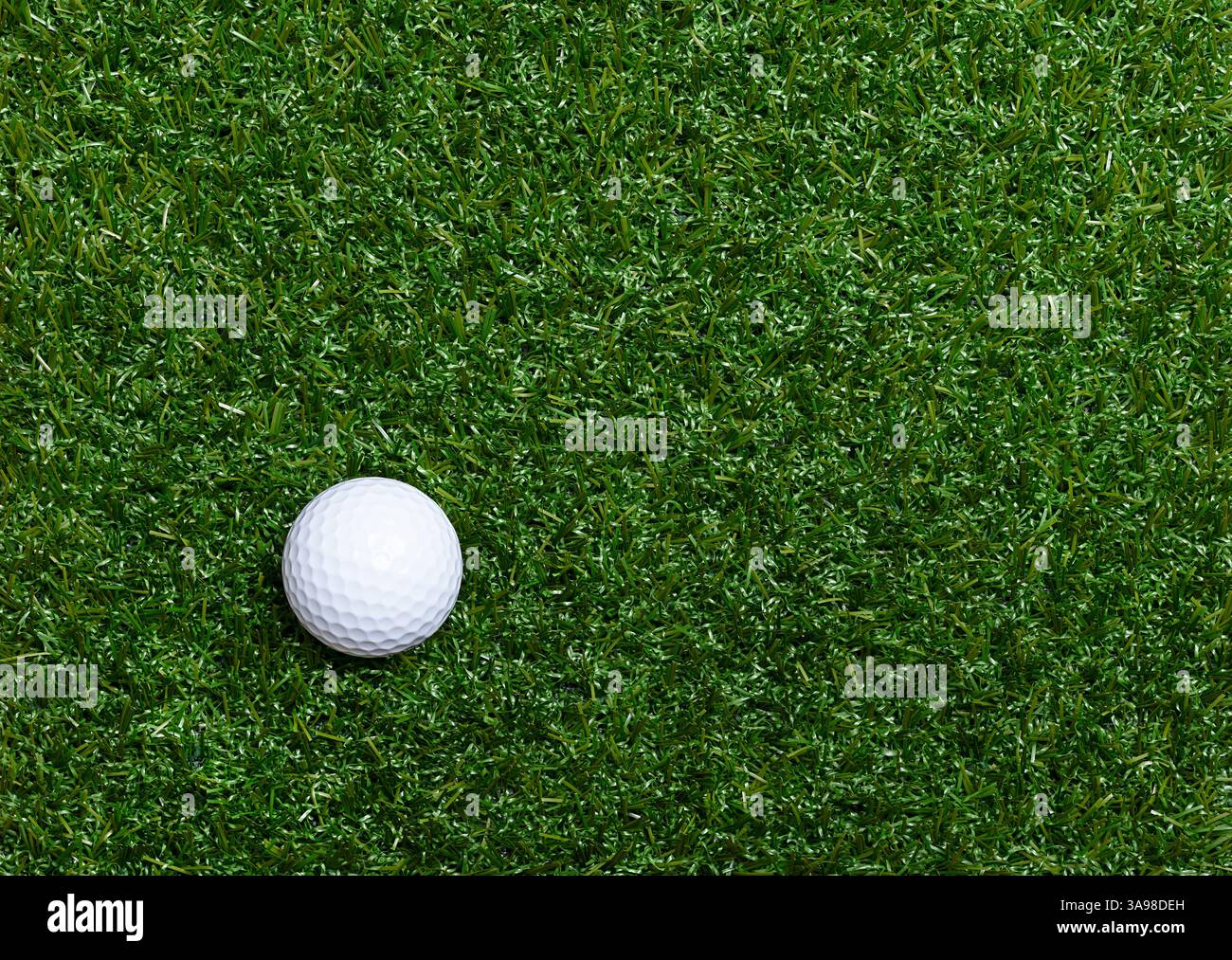 Golf ball on artificial turf. Single, white American golf ball with special notches, on the ...