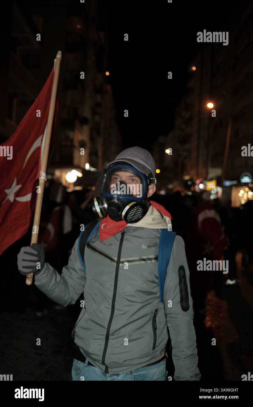 Izmir, Turkey. 29th Mar, 2025. A protester in a gas mask holds a ...