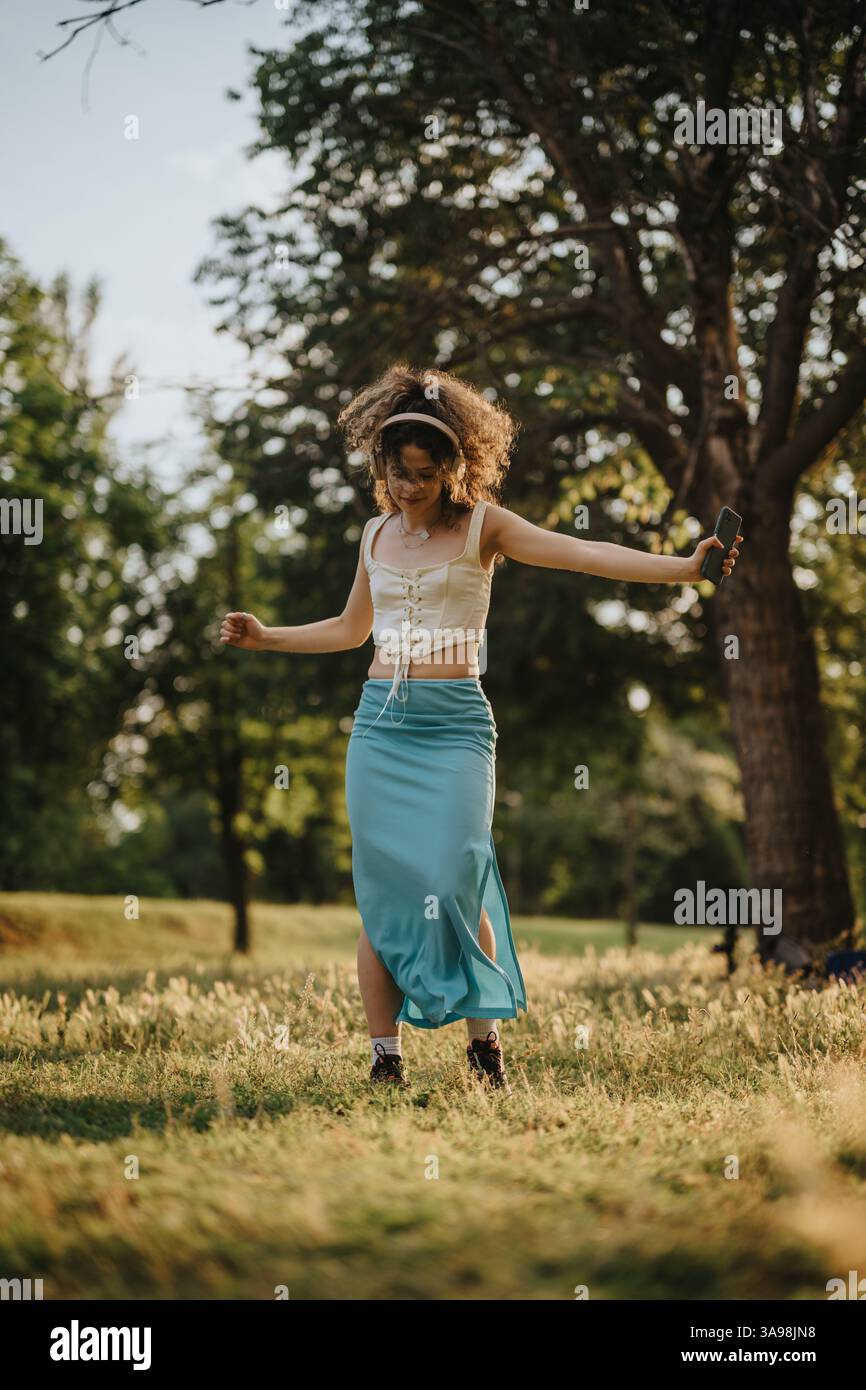 Young woman dancing gracefully in a sunny park setting Stock Photo - Alamy