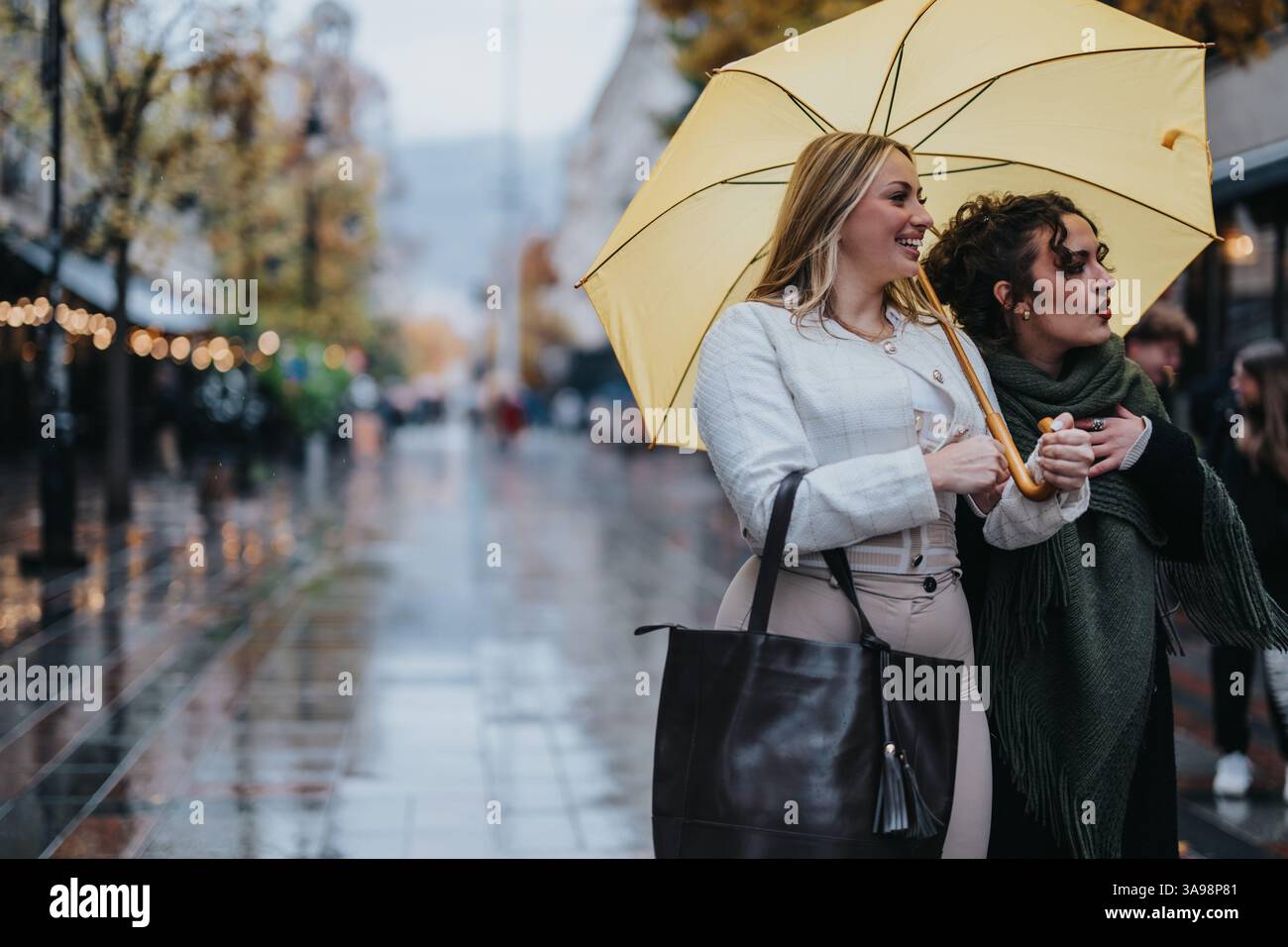 Two Women Sharing a Yellow Umbrella on a Rainy Day Stroll Stock Photo - Alamy