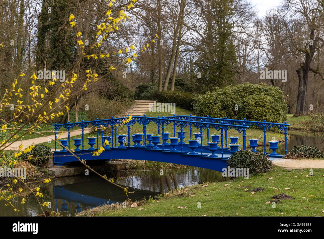 30 March 2025, Saxony, Bad Muskau: A blue-painted bridge spans a small ...