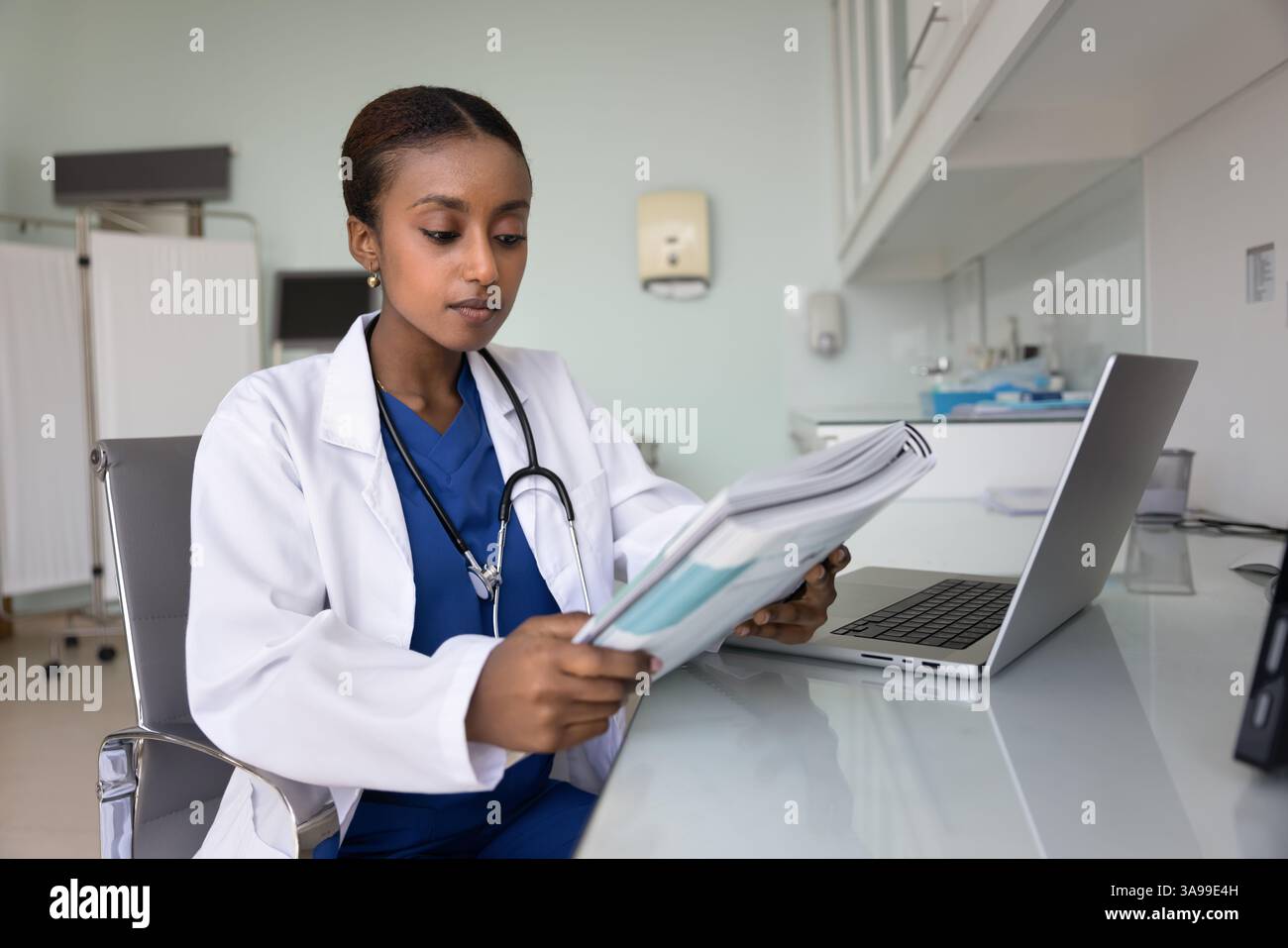 Serious young African doctor woman reading paper medical records Stock ...