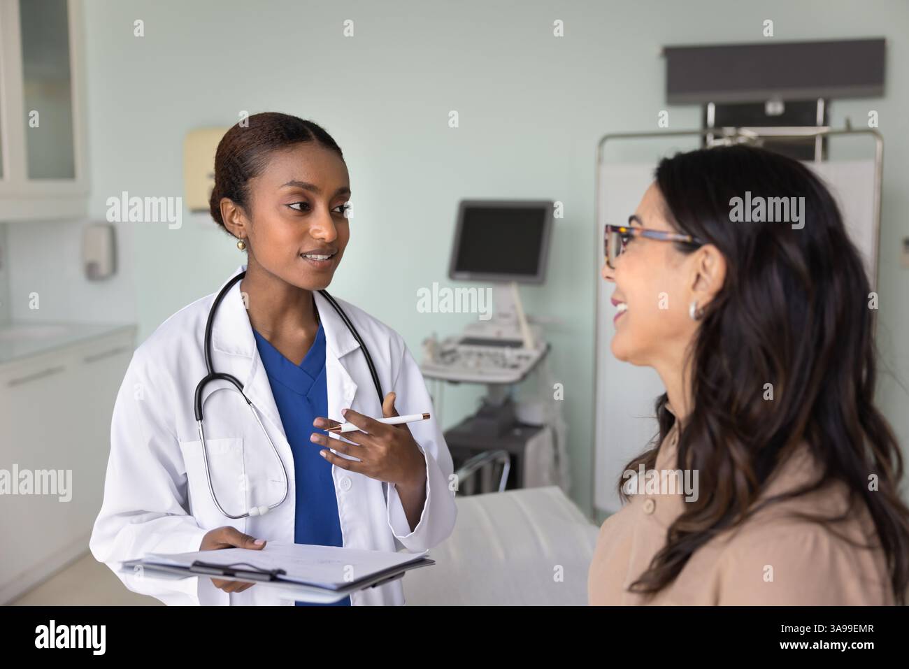 Friendly African doctor talking to senior patient in examination room ...