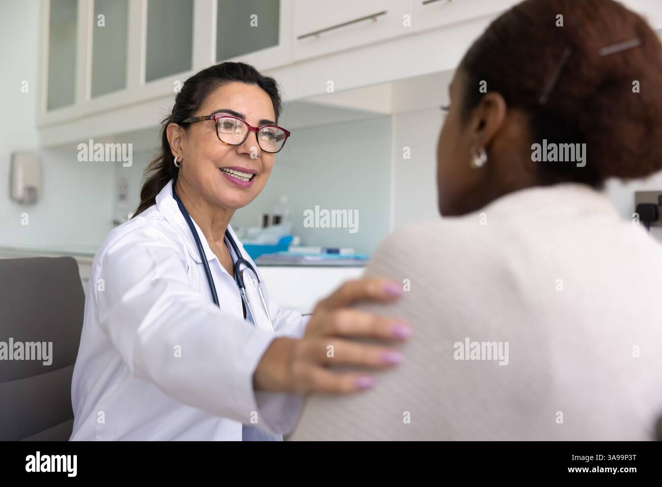 Happy positive senior doctor talking to young patient Stock Photo - Alamy