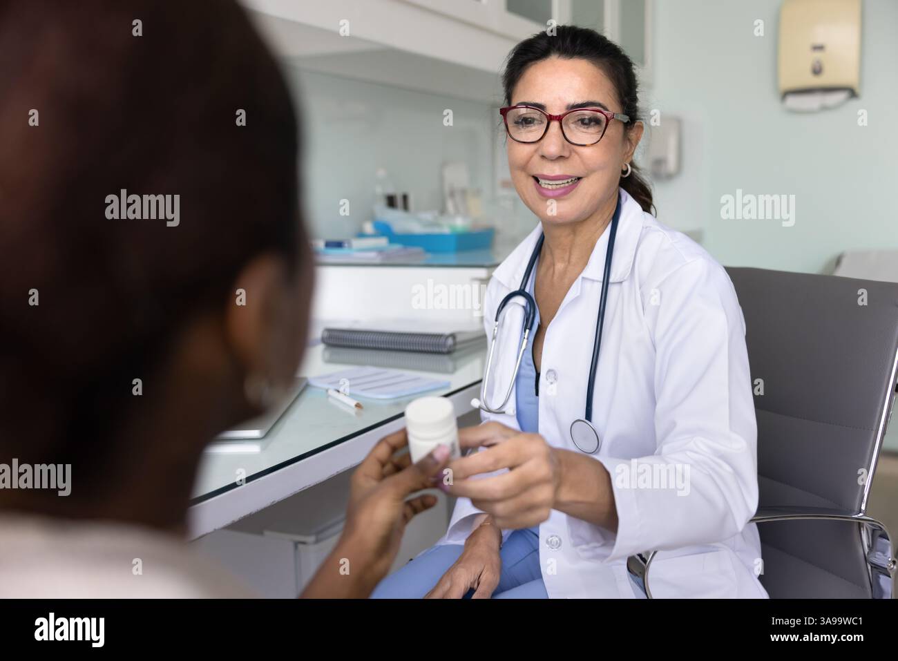 Happy practitioner doctor giving bottle of pills to female patient ...
