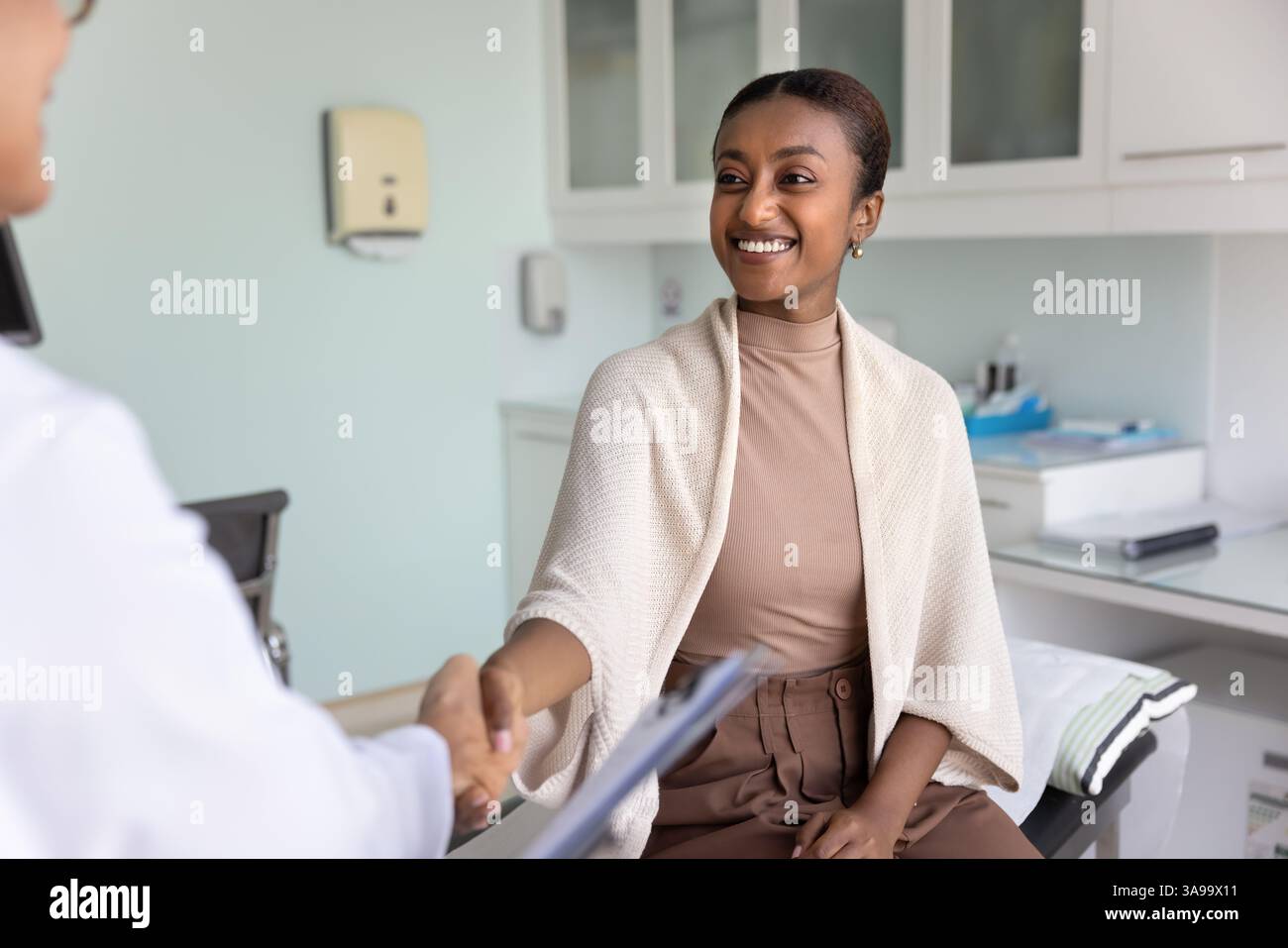 Positive healthy young African patient giving handshake to female ...