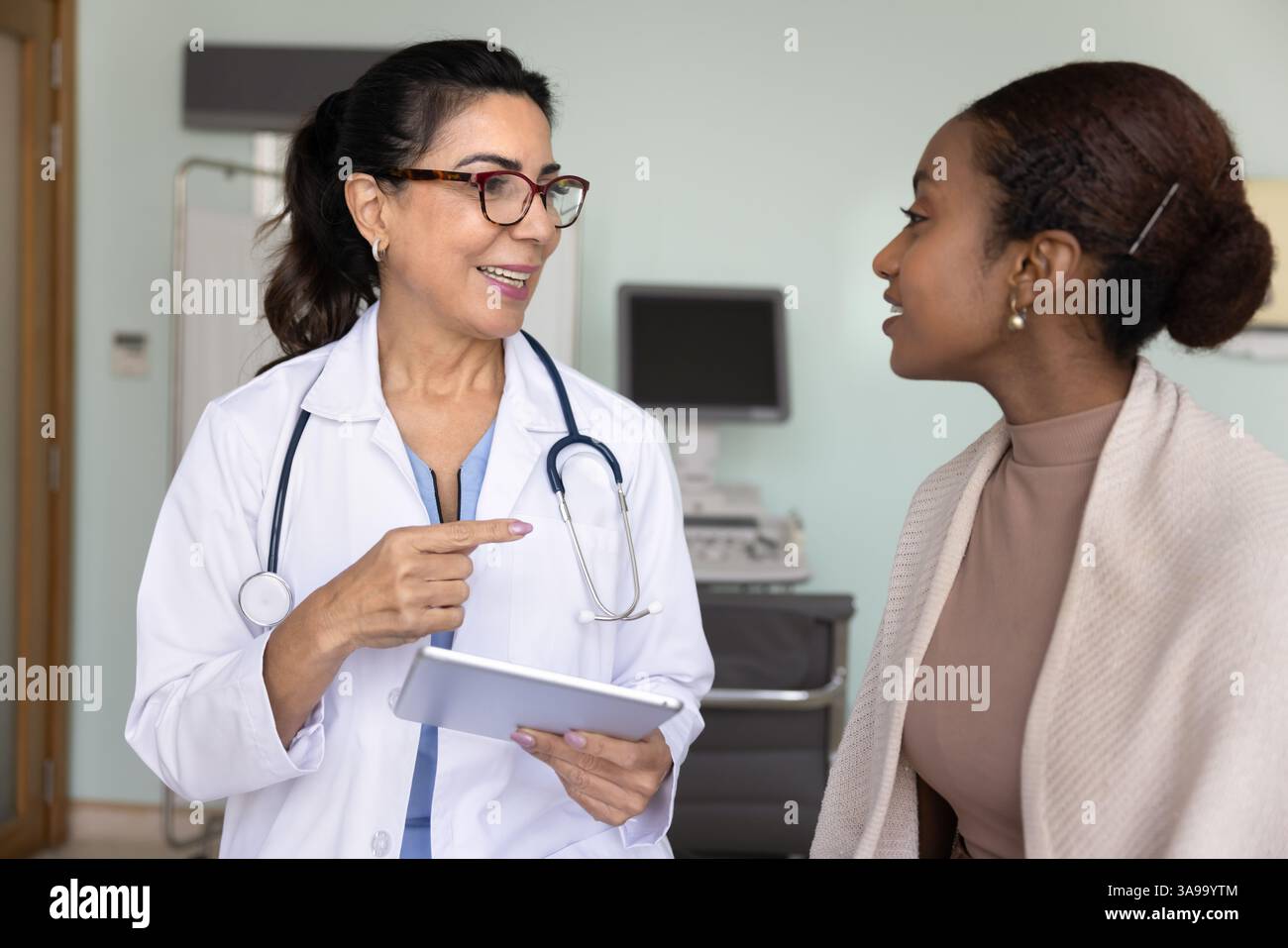 Positive Latin female doctor talking to young Black patient woman Stock ...