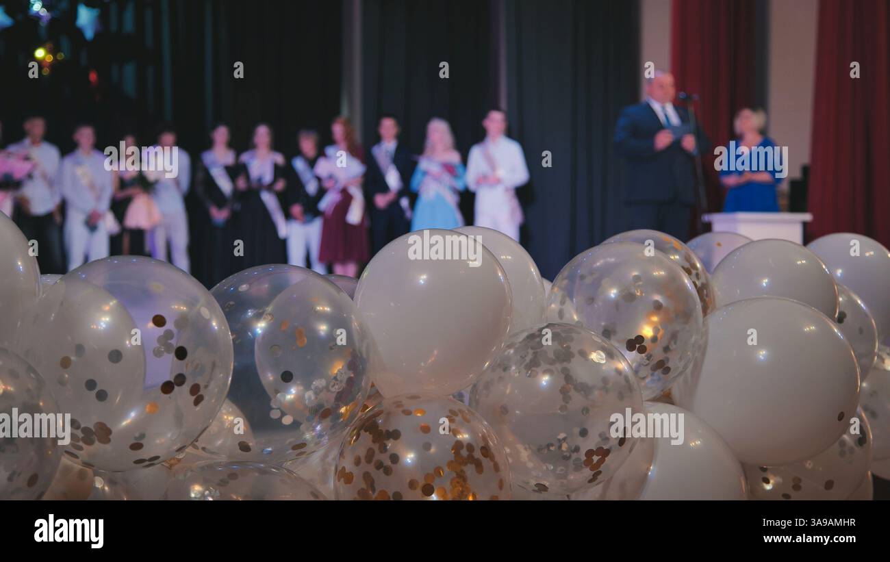White balloons, gold and silver confetti surrounding graduating ...