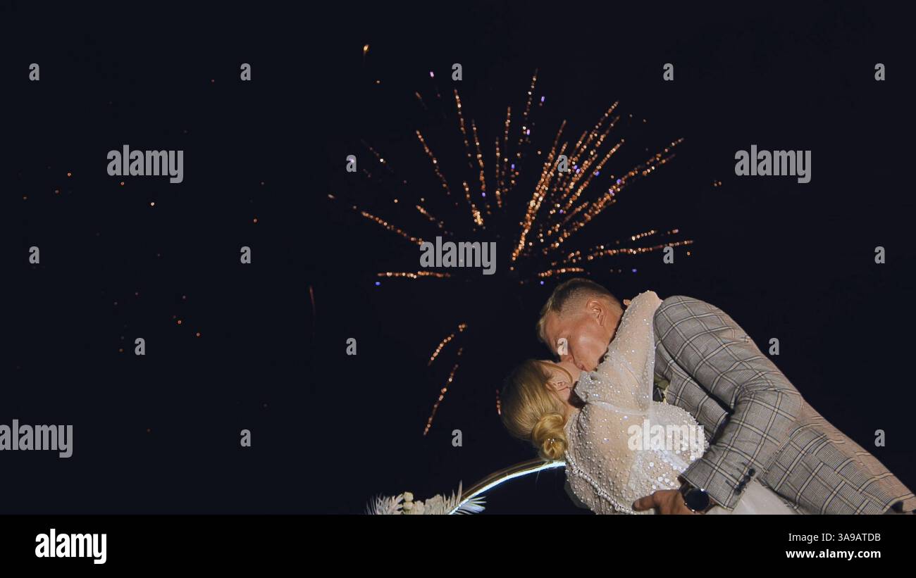 Romantic couple kissing under exploding fireworks during night wedding ...