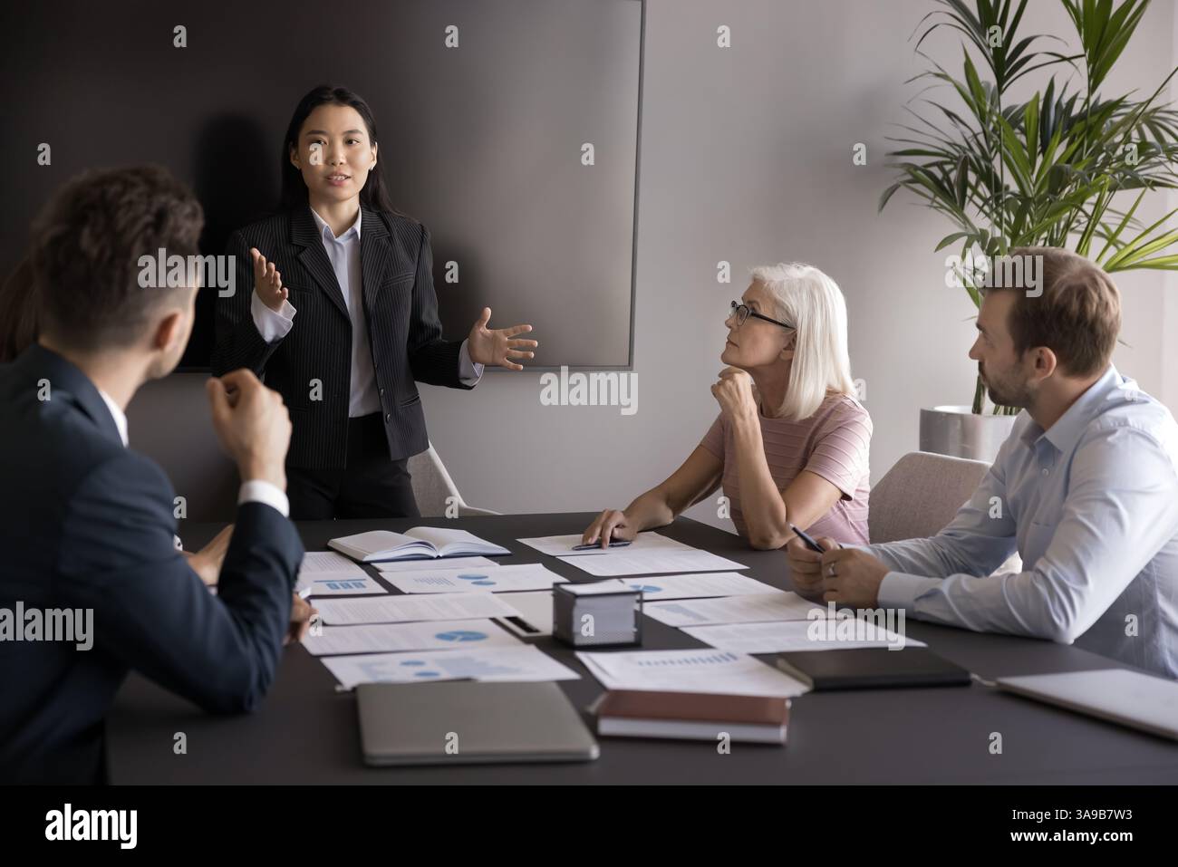 Serious Asian business woman addressing speaking to meeting ...