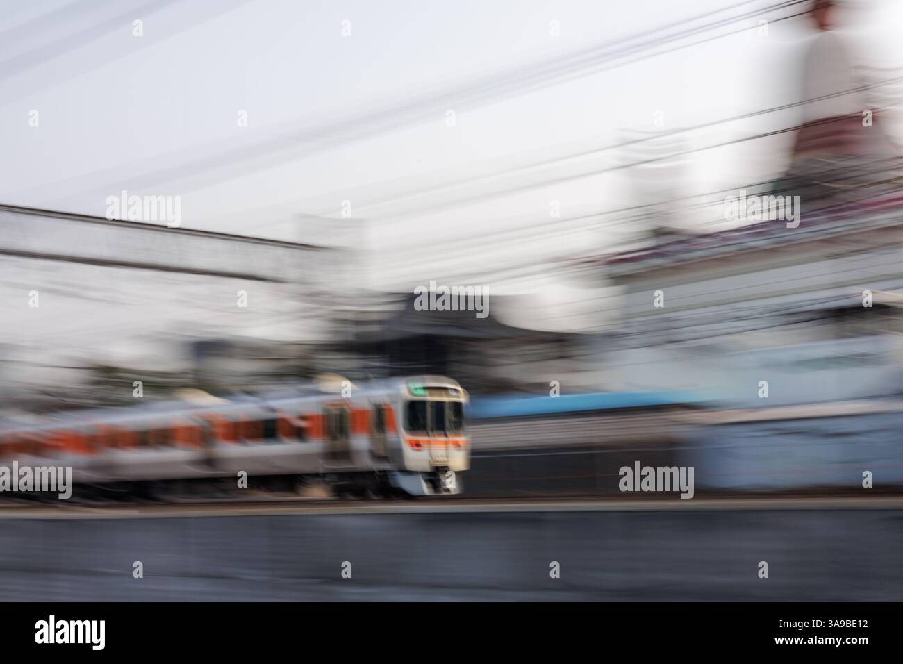 Japanese commuter train races through an urban area. Motion blur ...