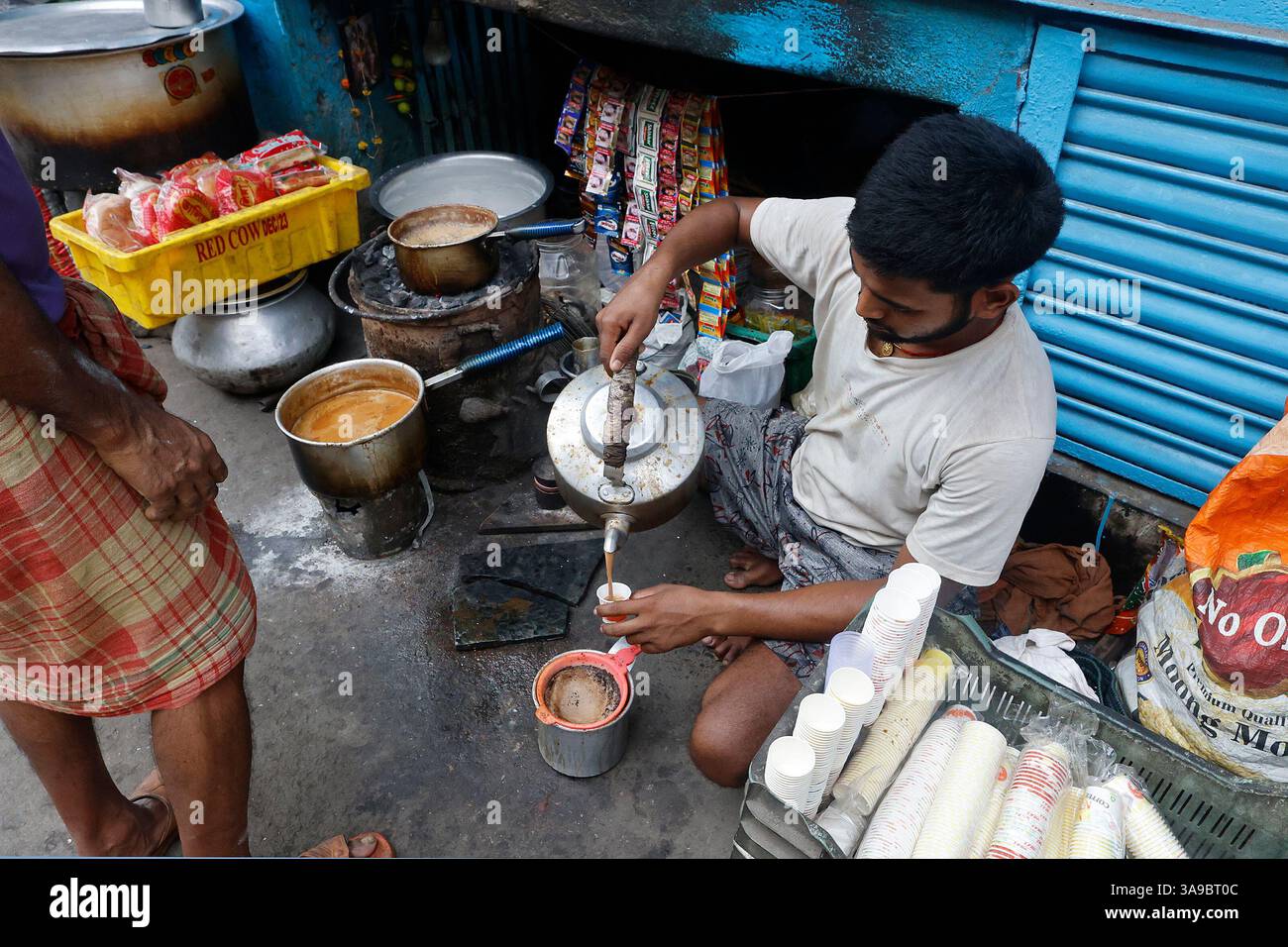 Chai vendor pouring tea into a disposable cup in Kolkata, West Bengal ...
