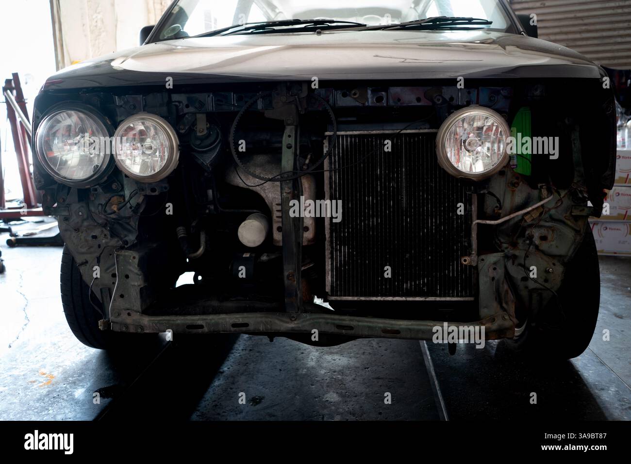 Front view of a car in a workshop with its bumper and grille removed ...