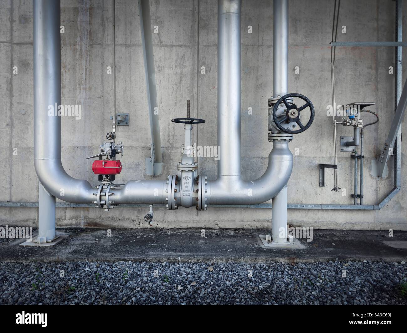 Pipe with a red valve on it. The valve is silver. The pipe is attached ...