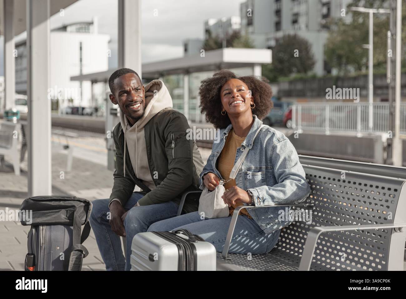 Loving couple having fun while waiting for a train sitting on a railway ...