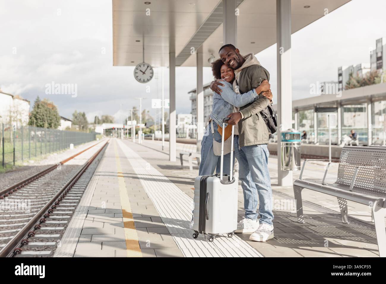 Happy young African American couple hugging at a train station, meeting ...