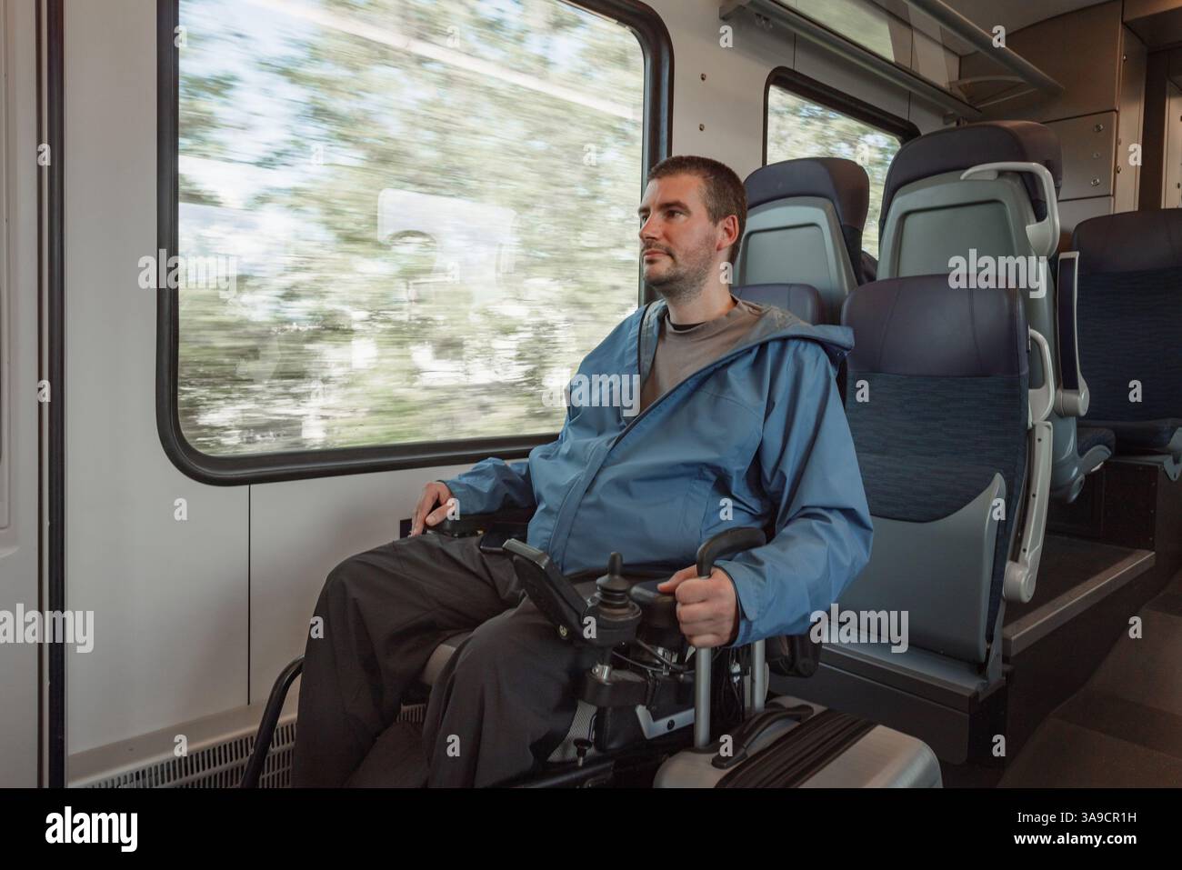 Man with physical disability on a rail journey, sitting in a wheelchair ...
