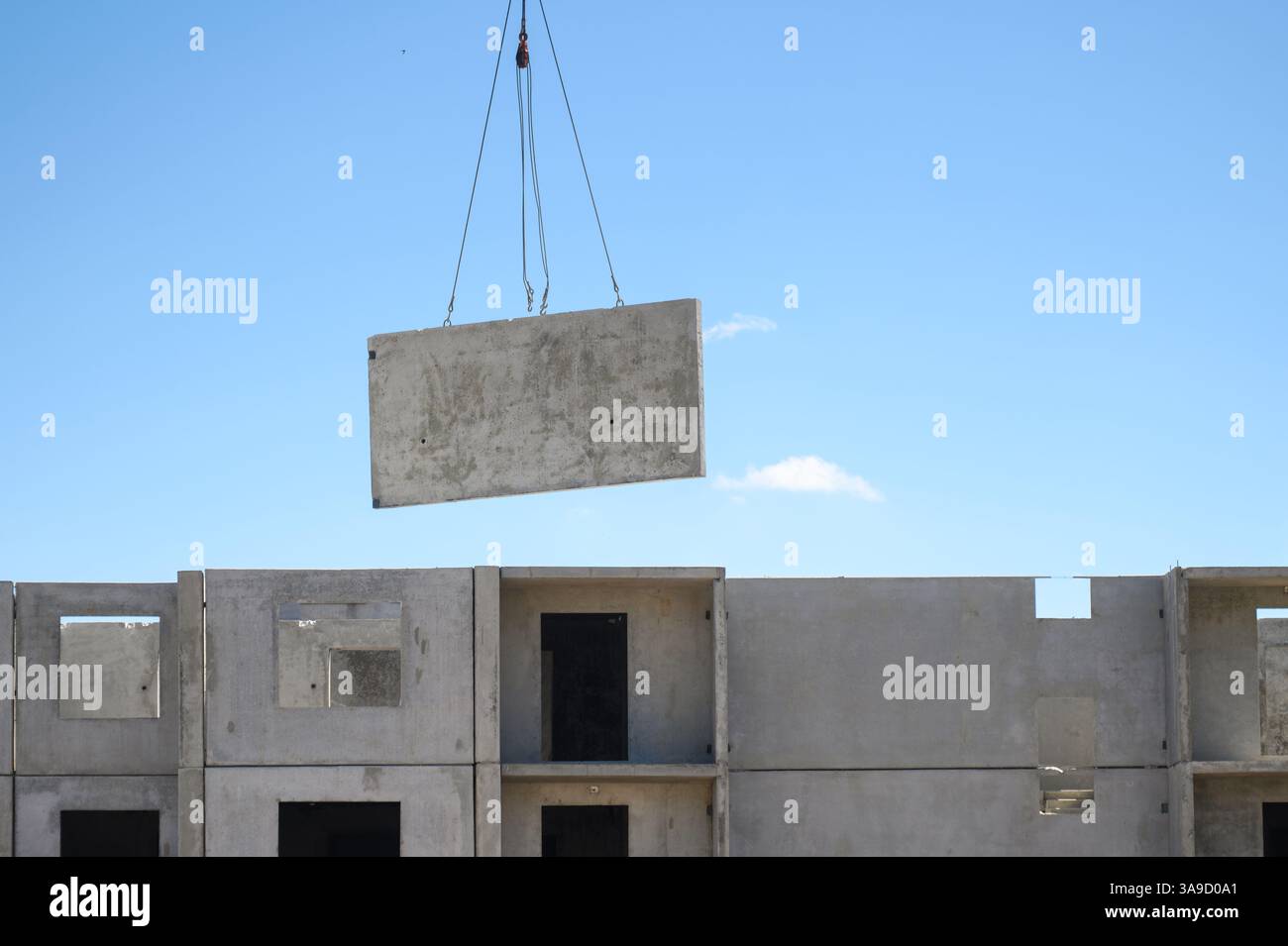 Construction crane on cables lifts panel for construction of multi ...
