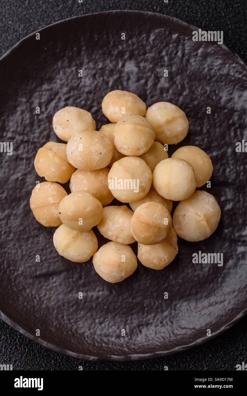 Raw peeled macadamia nut in ceramic bowl on dark concrete background ...