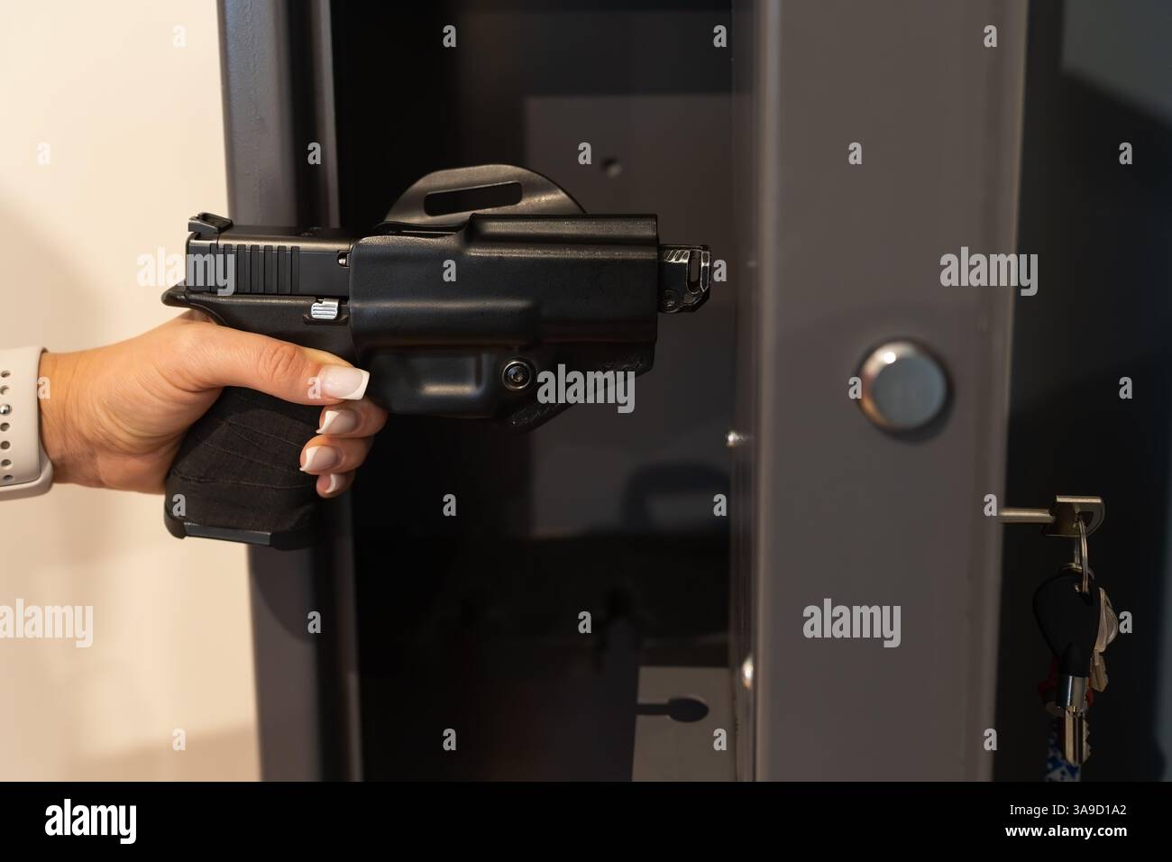 Safe firearm storage: a woman's hand places a pistol in a holster into ...