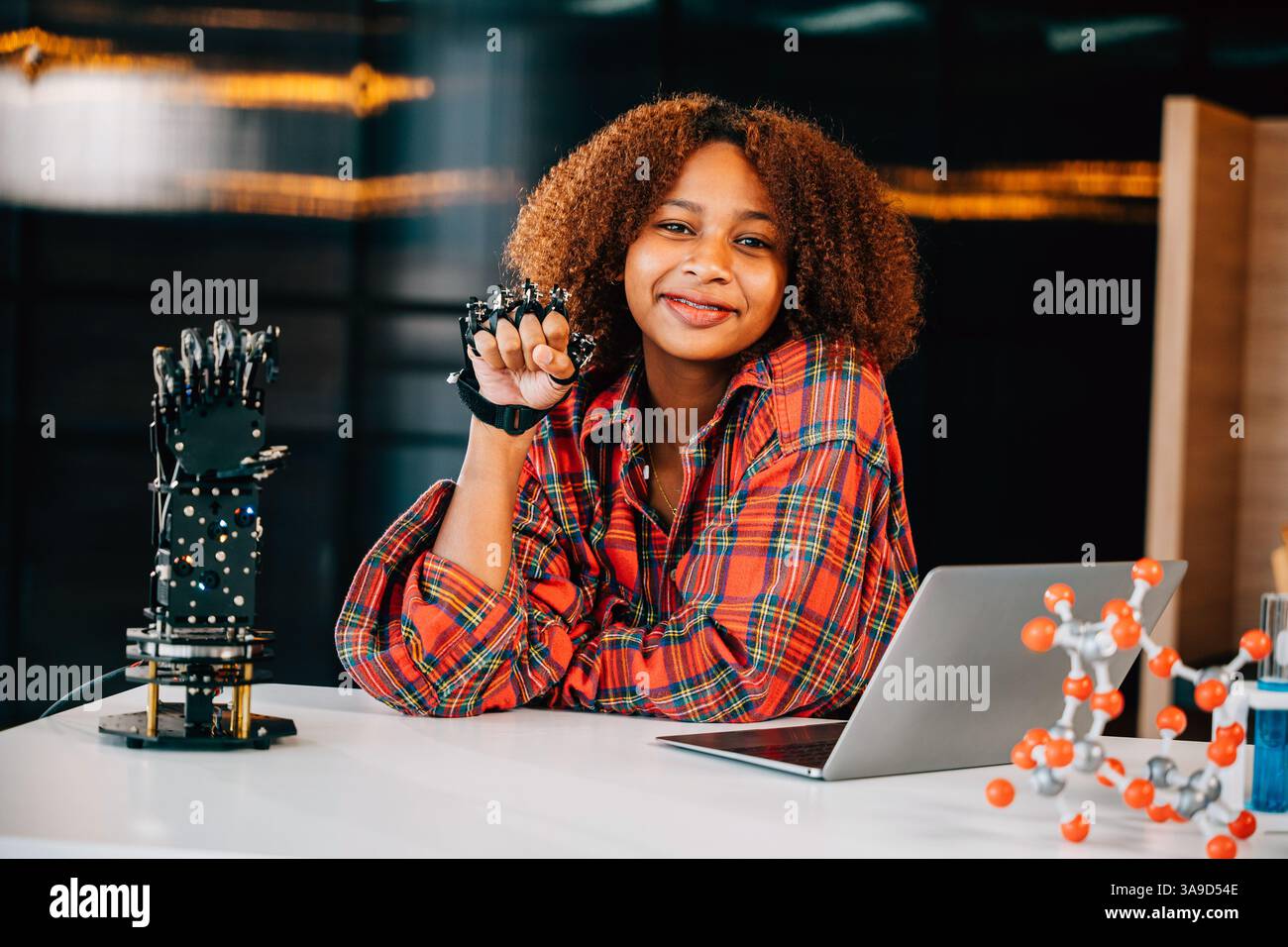 Black teenage student tests a robotic arm in a classroom engaging in ...