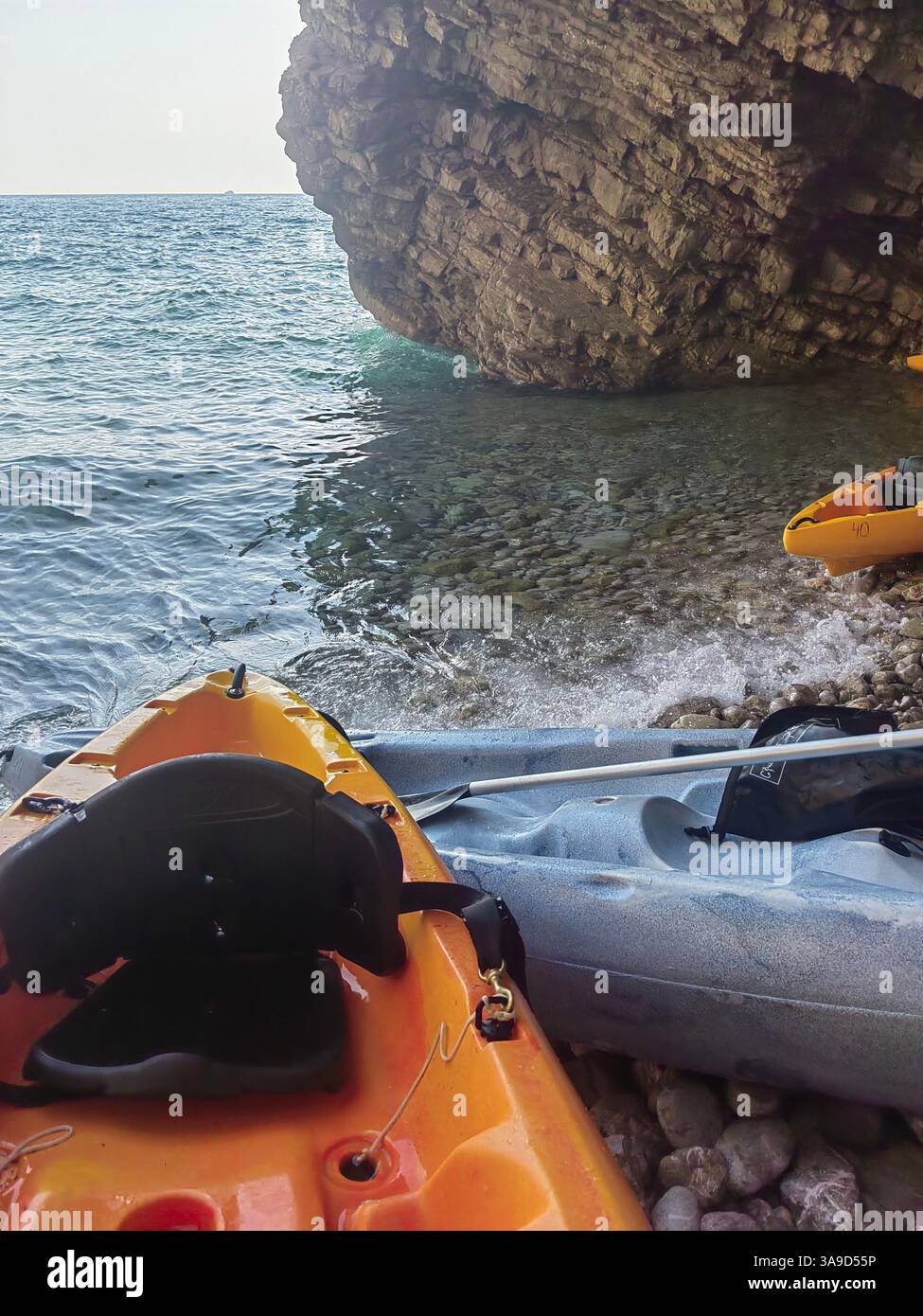 Sea Kayaks Resting on a Rocky Beach Near a Cliffside Cave Stock Photo ...