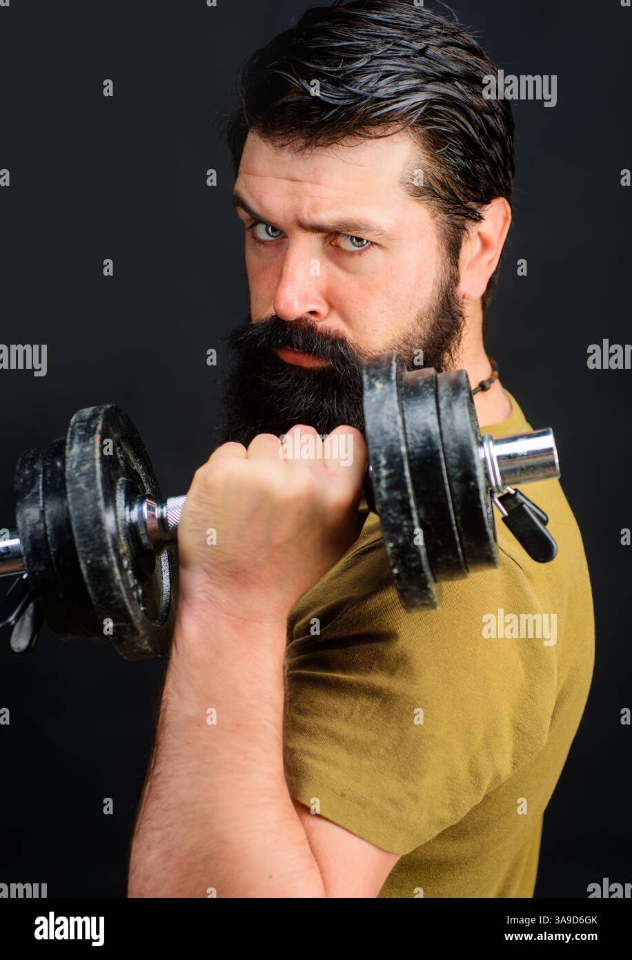 Strong man training with dumbbells in sports club. Athlete man raises ...