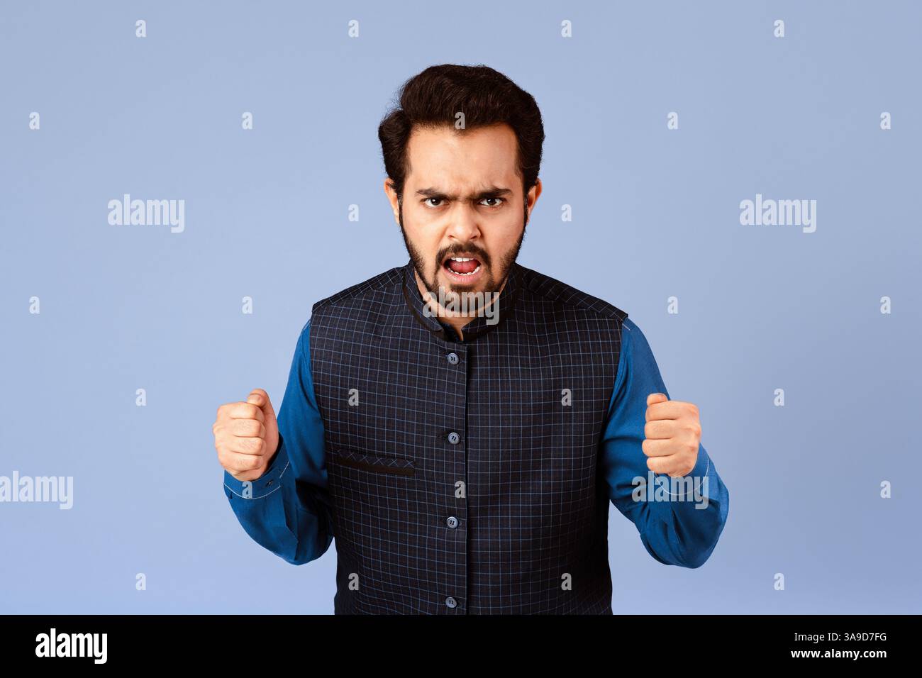 Millennial Indian man clenching his fists in anger against color ...