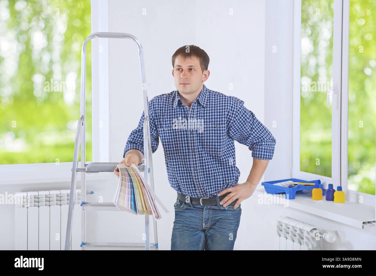 A young men standing near the stepladder holding color palette and ...