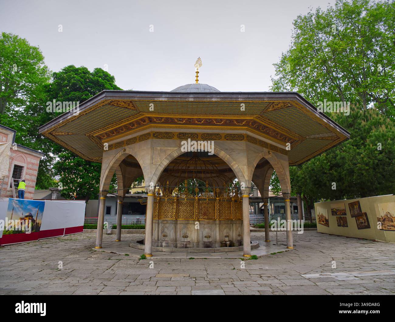 Ornate hexagonal fountain pavilion with gold decorations in a garden ...