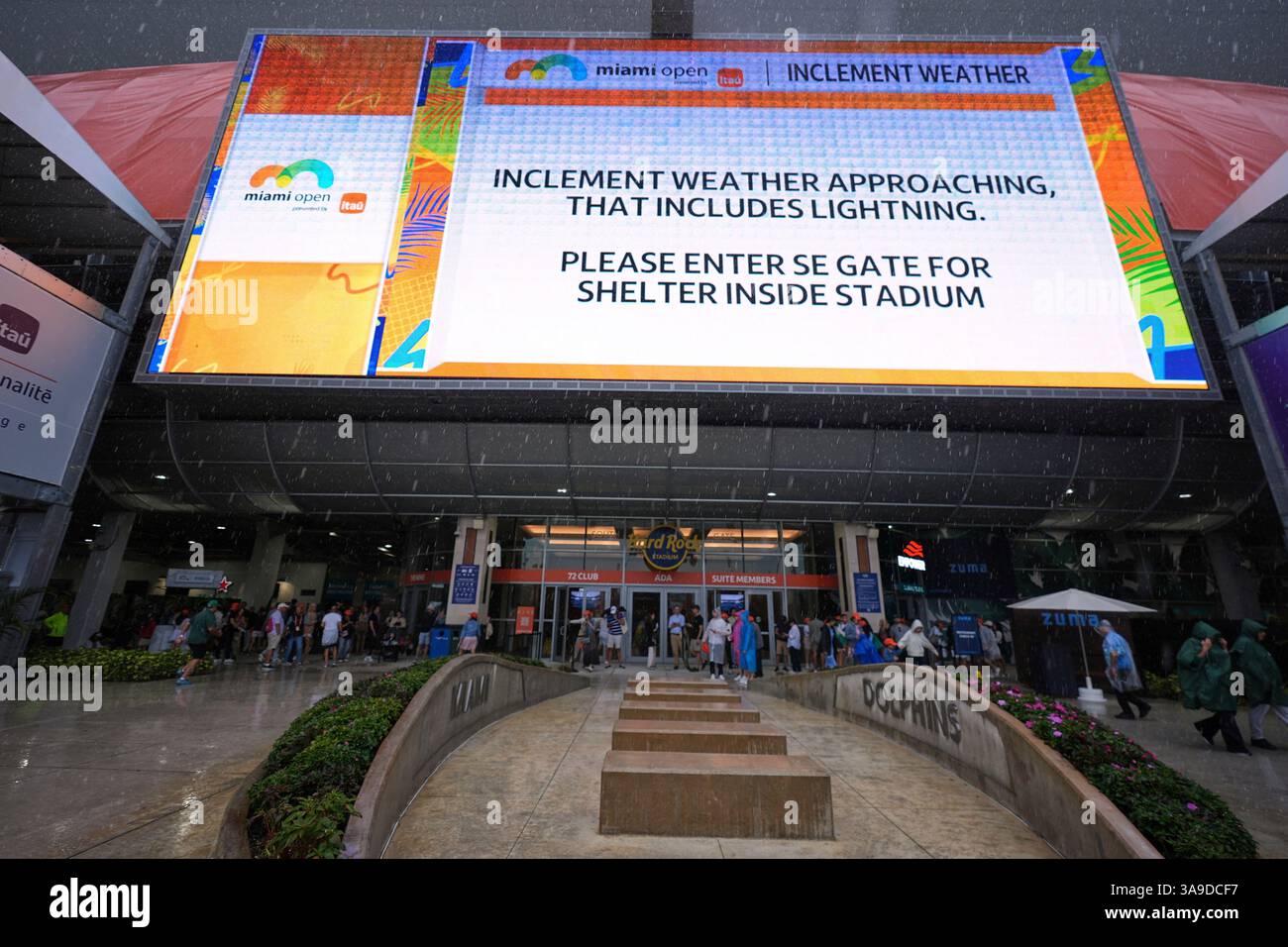 Fans shelter under an overhang outside Hard Rock Stadium during an ...