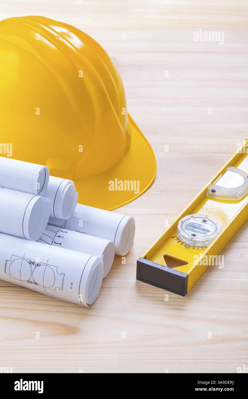 Yellow construction level hardhat and blueprints Stock Photo - Alamy